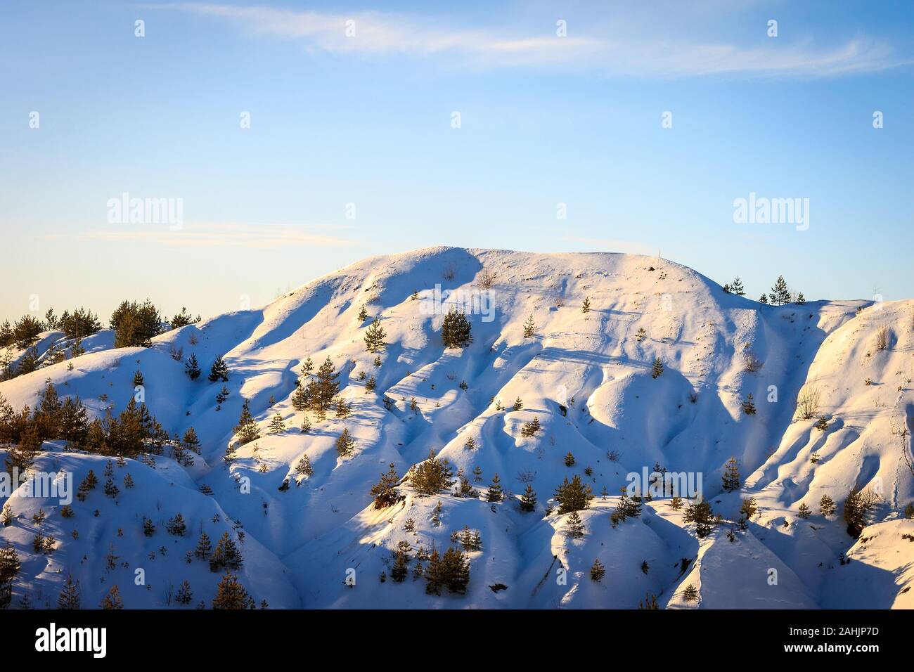 Hills covered with snow in winter with pines, trees and blue sky ...