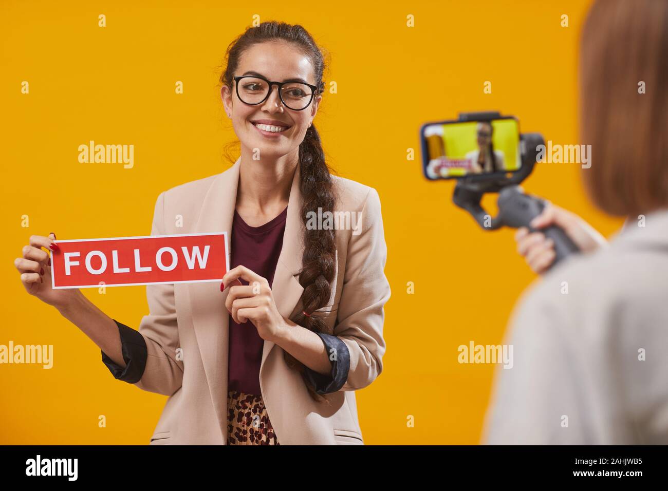Waist up portrait of contemporary young woman holding Follow word while ...