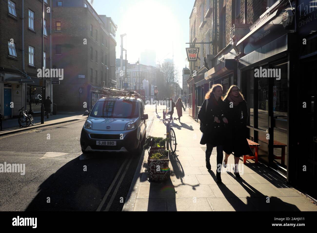 A view two women people walking past shops along Pitfield Street on an ...
