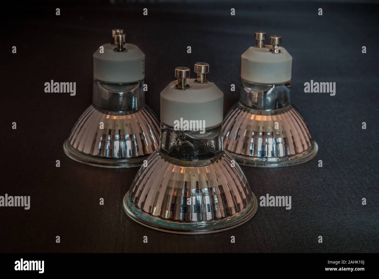 Three halogen light bulb units facing down on a black background ...