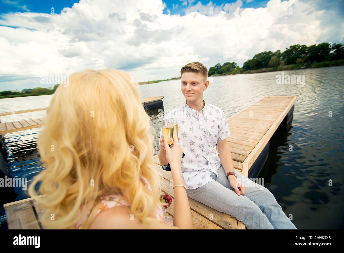 Romantic date surprise. A young guy and a girl on a wooden pier. Raise ...