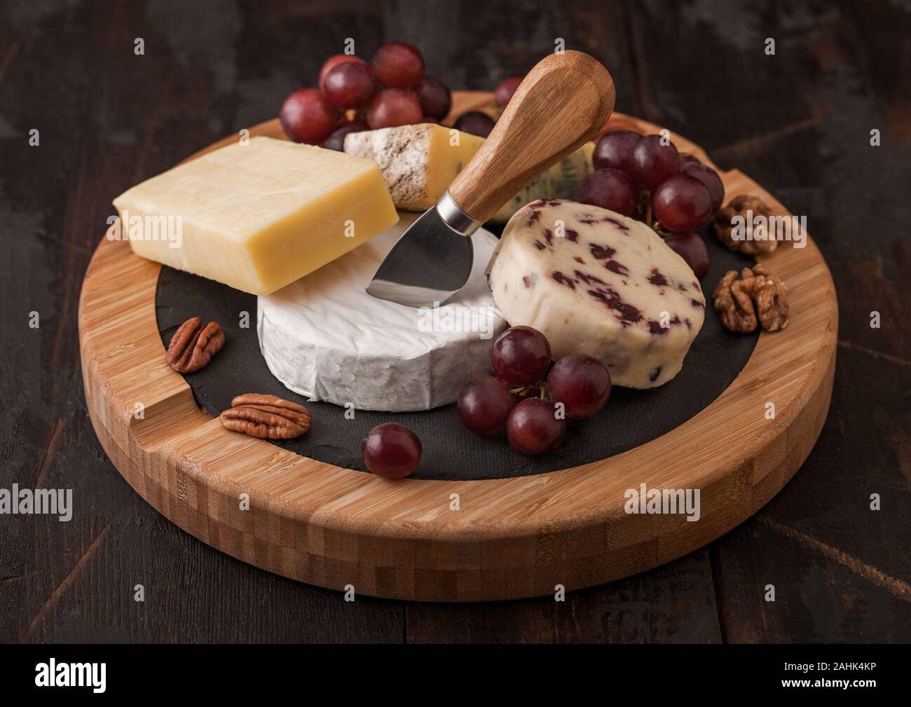 Selection of various cheese on the board and grapes on wooden table ...