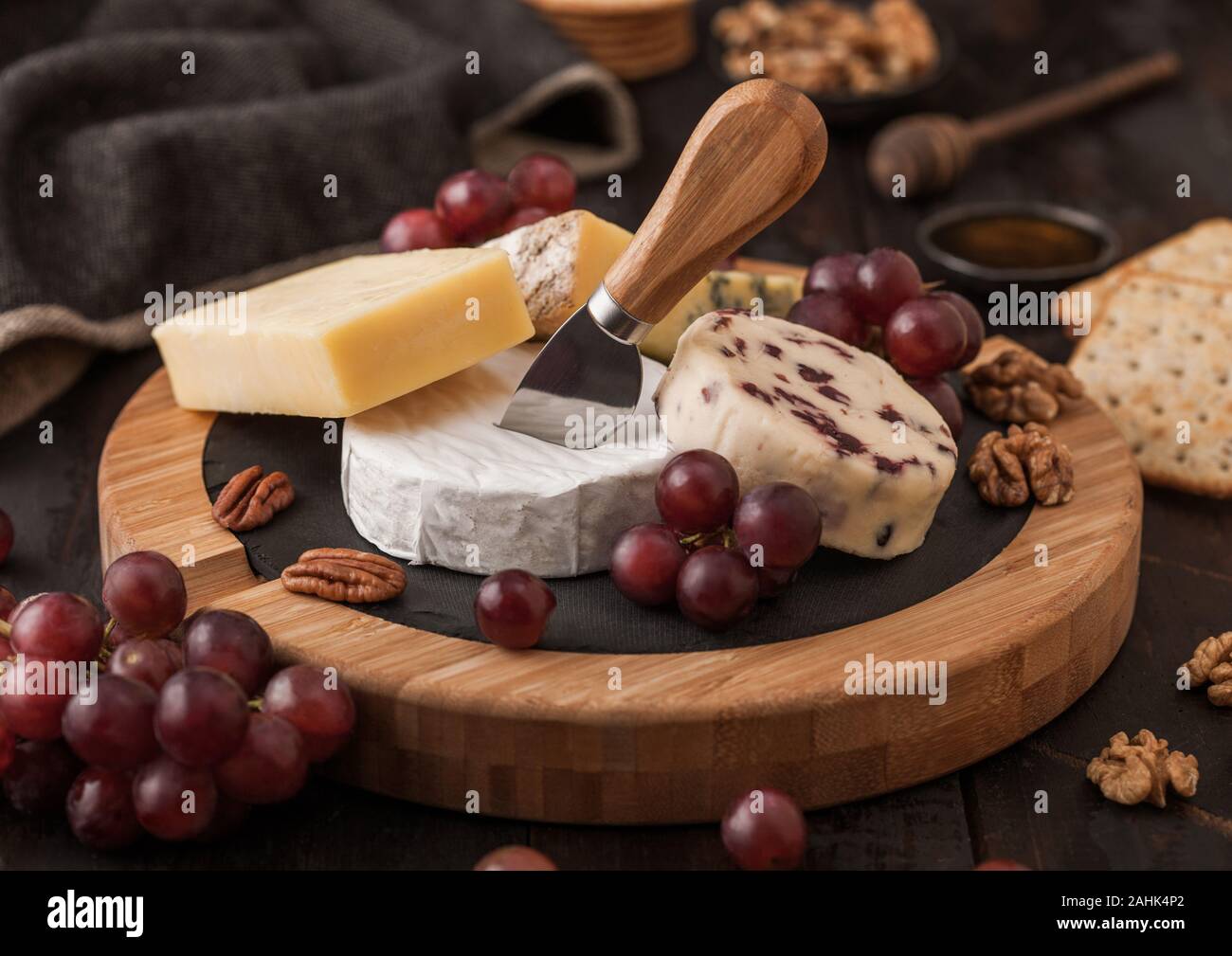 Selection of various cheese on the board and grapes on wooden table ...