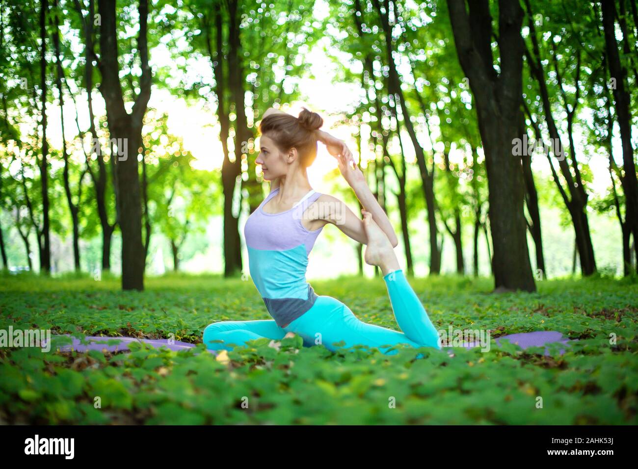 A young sports girl practices yoga in a quit green summer forest, yoga ...