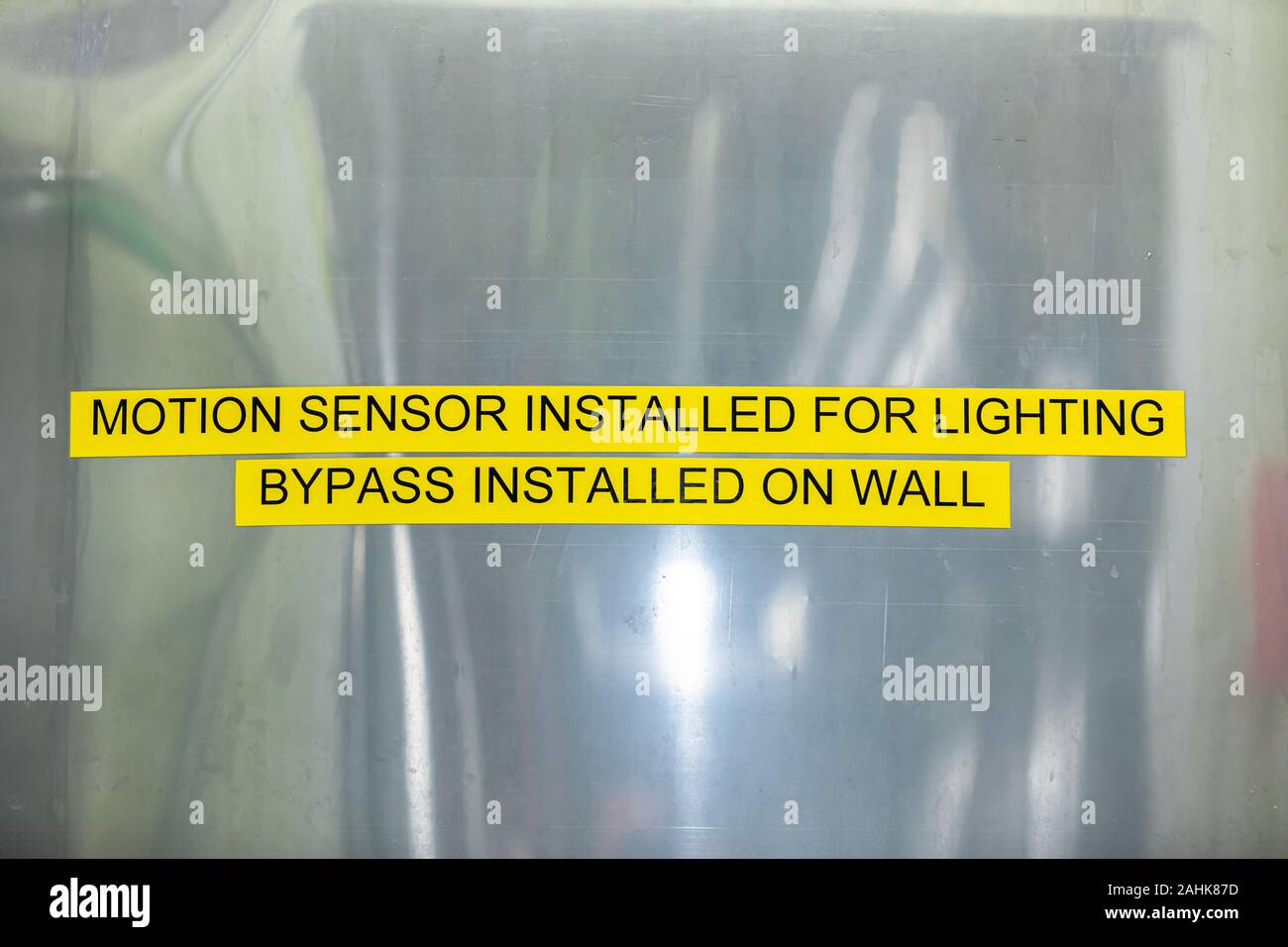 yellow sign with black text, on a stainless steel tank wall, motion ...