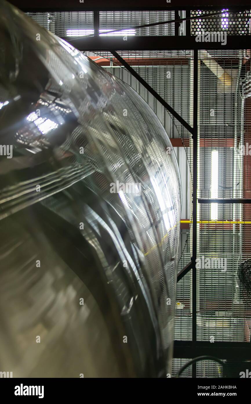 large big stainless steel tank or vessel against roof light and walking ...