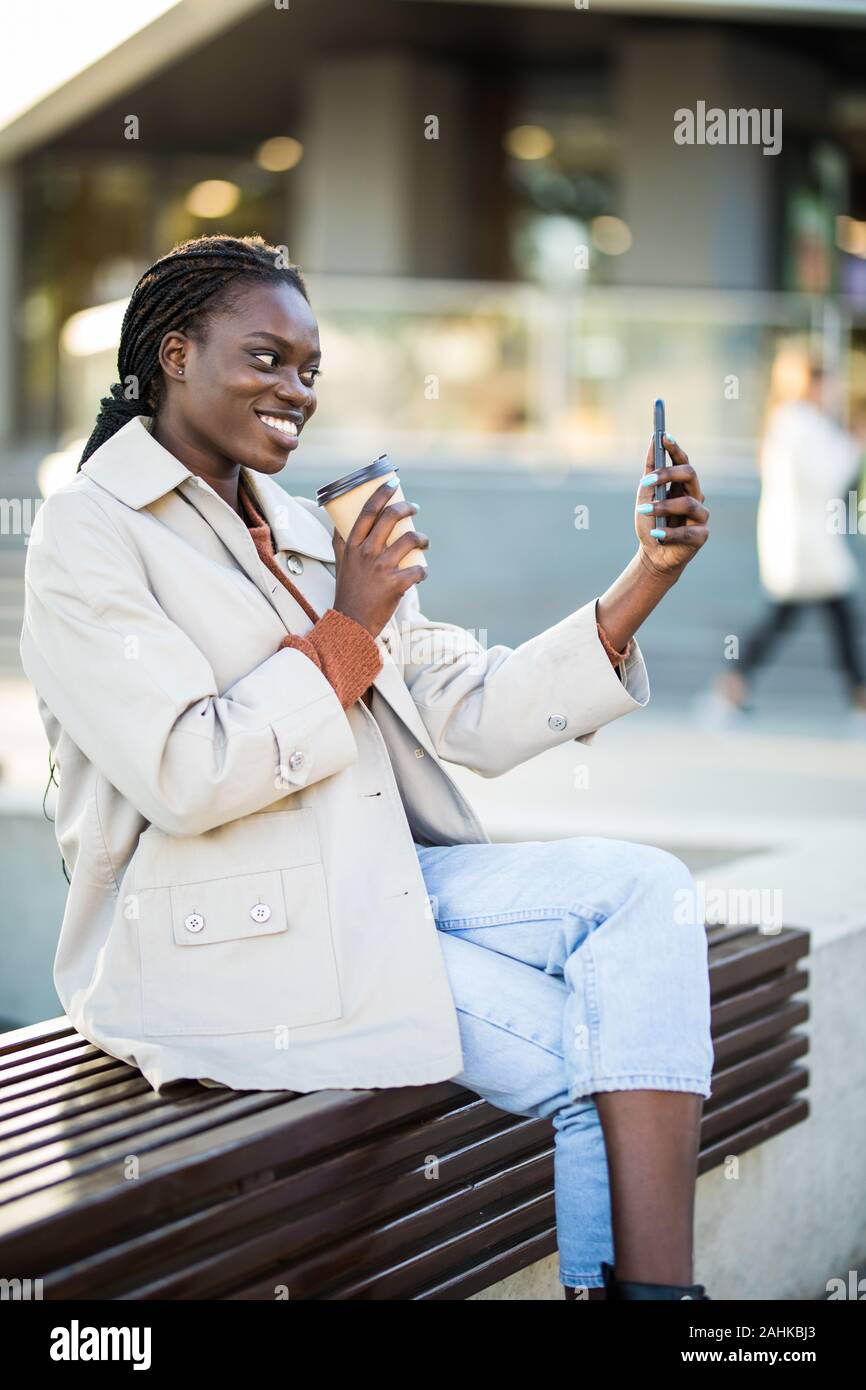 Cheerful African Woman Walking Outdoors Holding Takeaway Coffee Cup