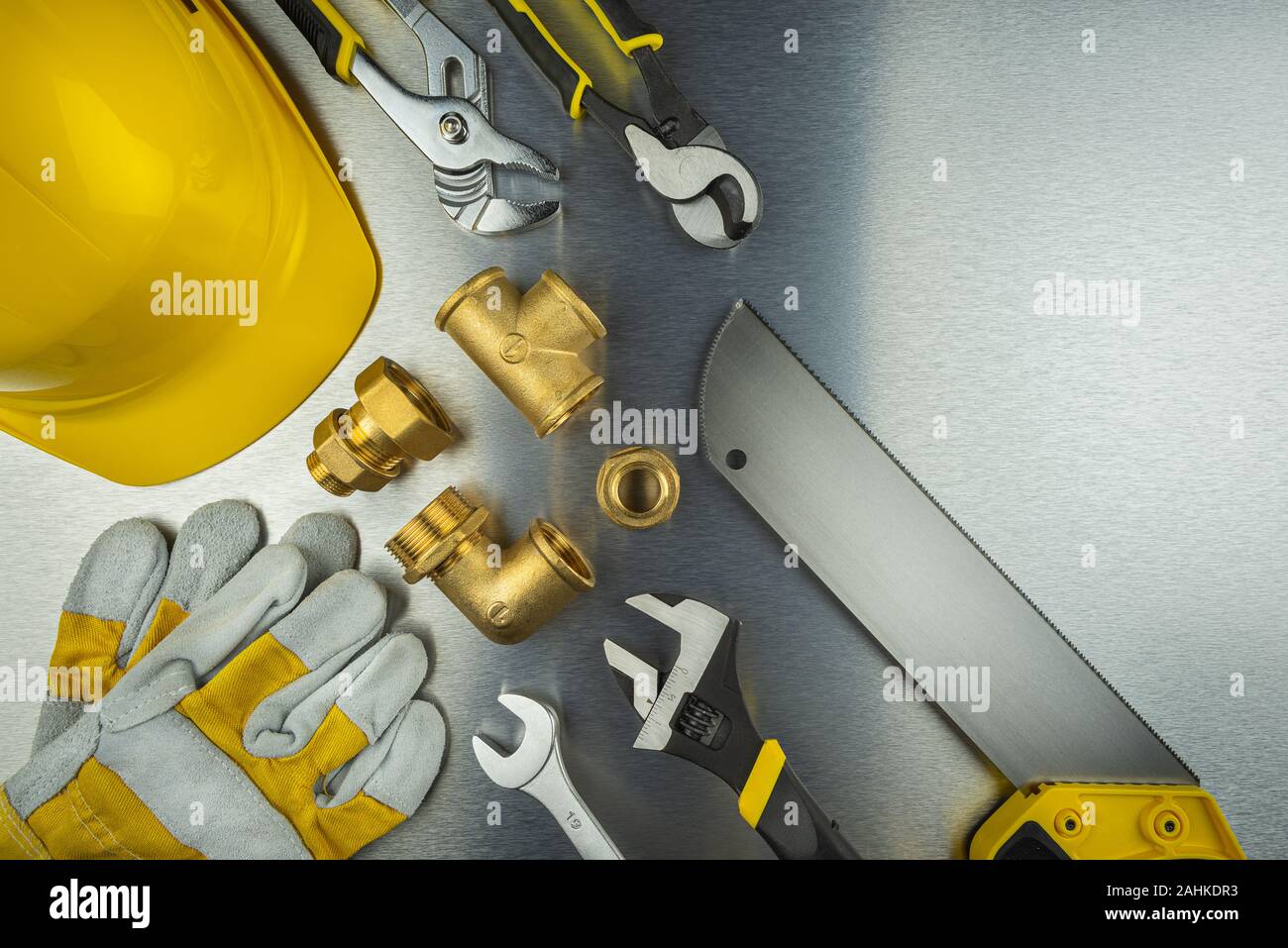 Plumber tools on brushed aluminum background with yellow helmet ...