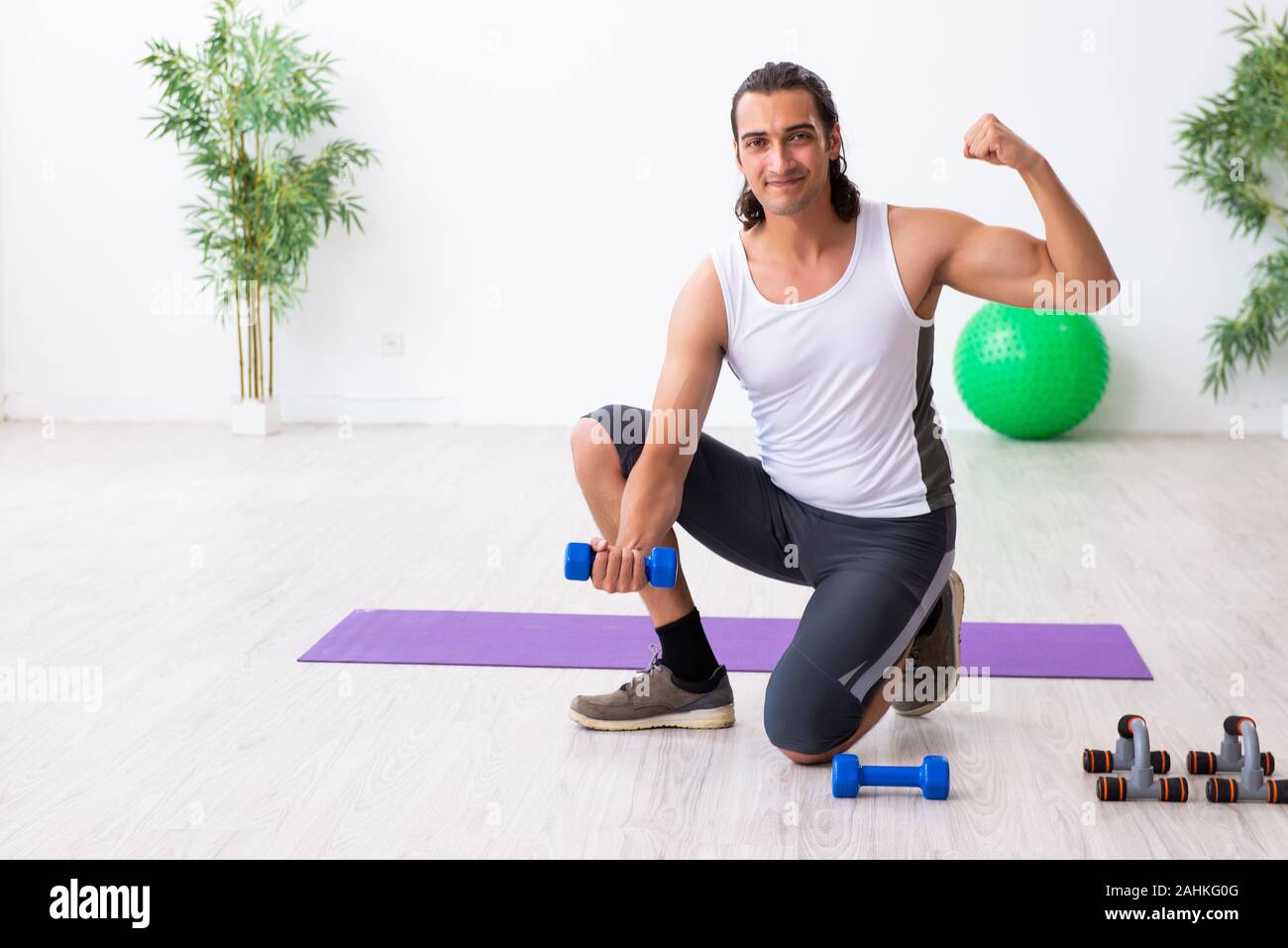 The young handsome man doing sport exercises indoors Stock Photo - Alamy