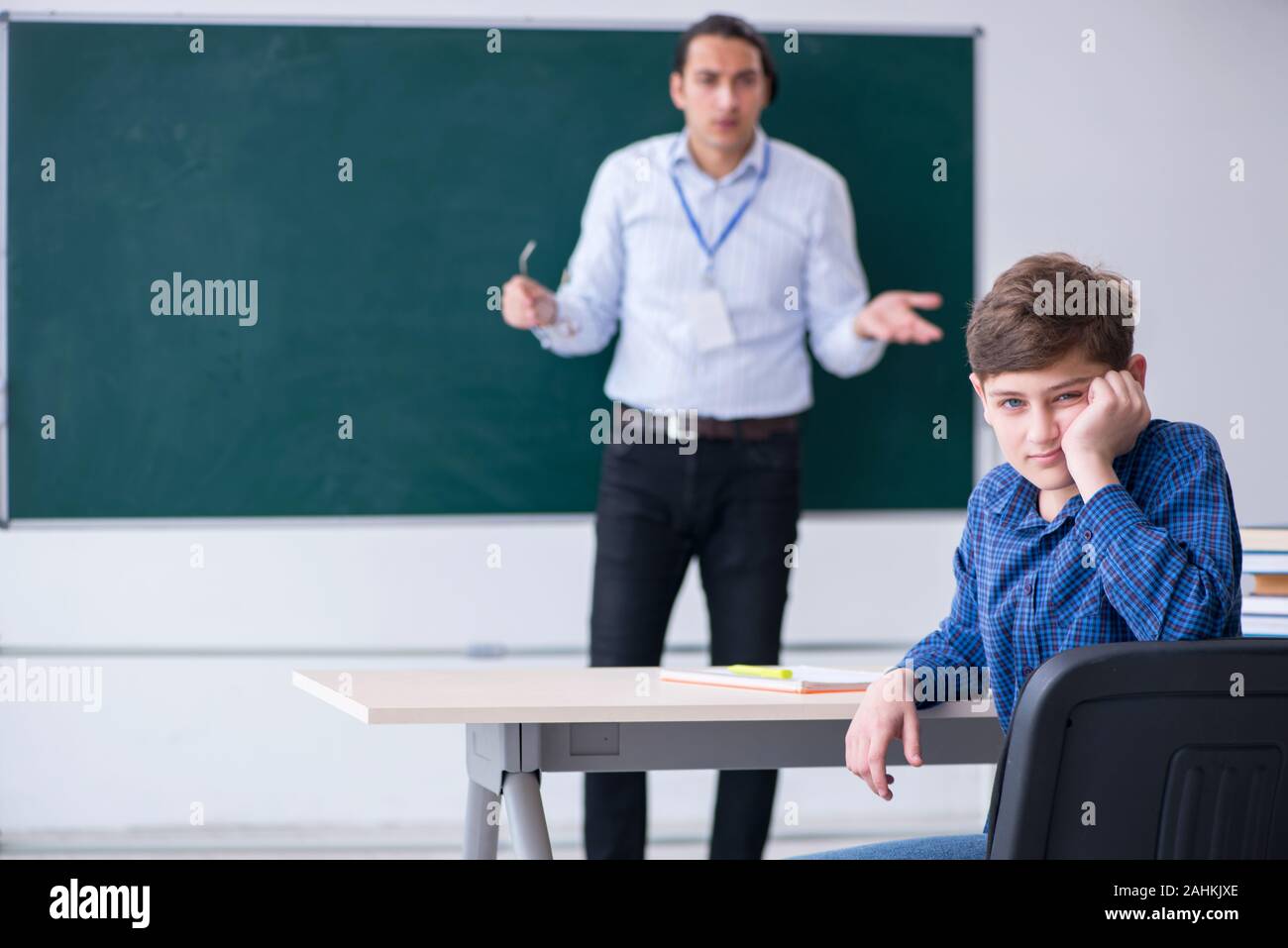 The young male teacher and boy in the classroom Stock Photo - Alamy