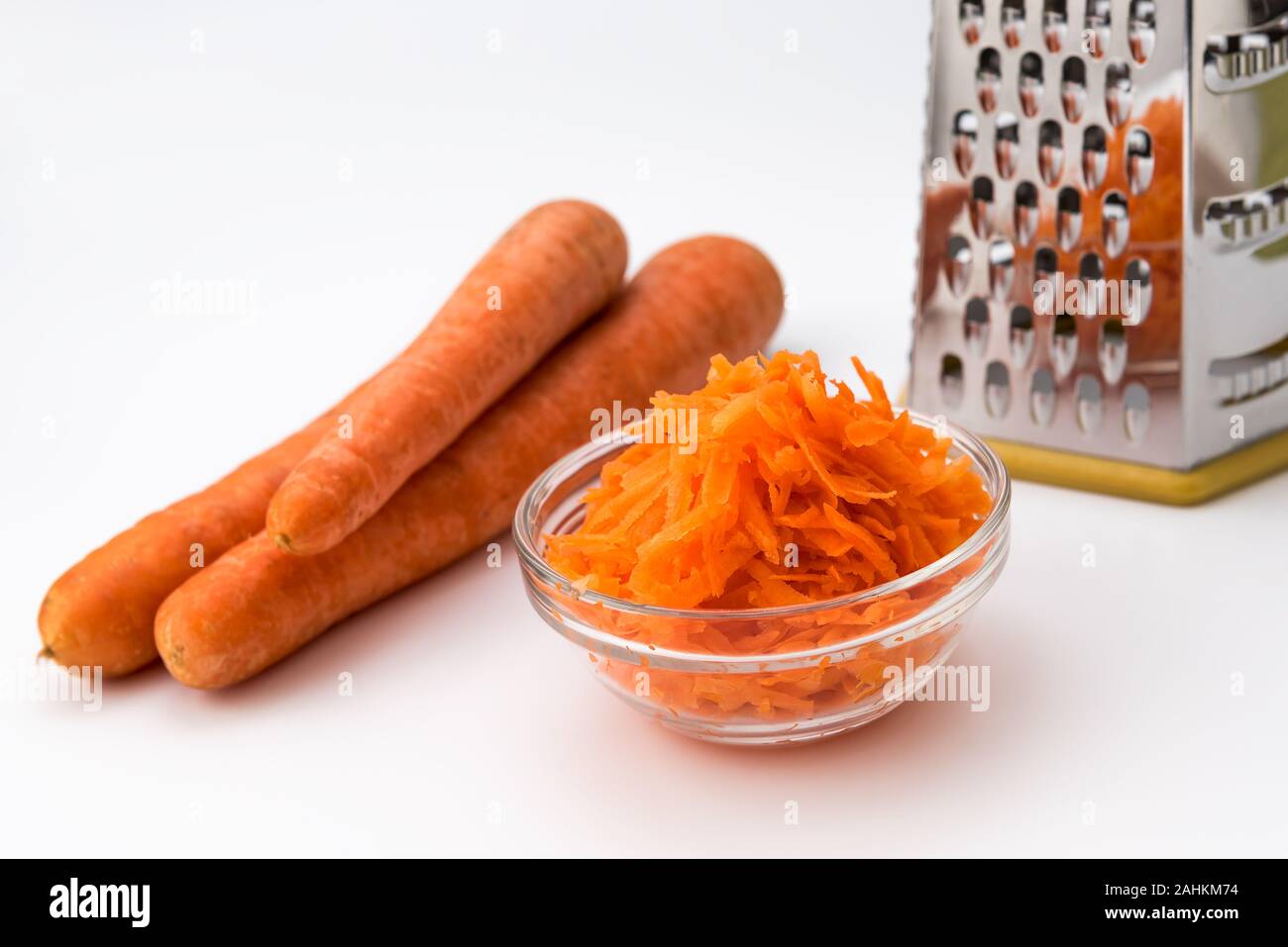 Fresh Grated carrot in a bowl and layout of carrots and grater isolated ...