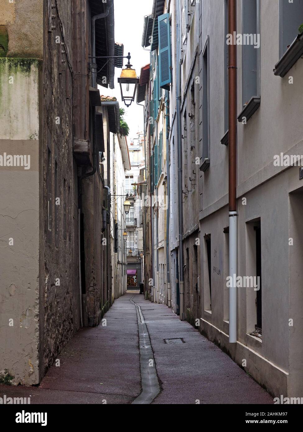 narrow alleyway with central drainage channel between tall buildings ...