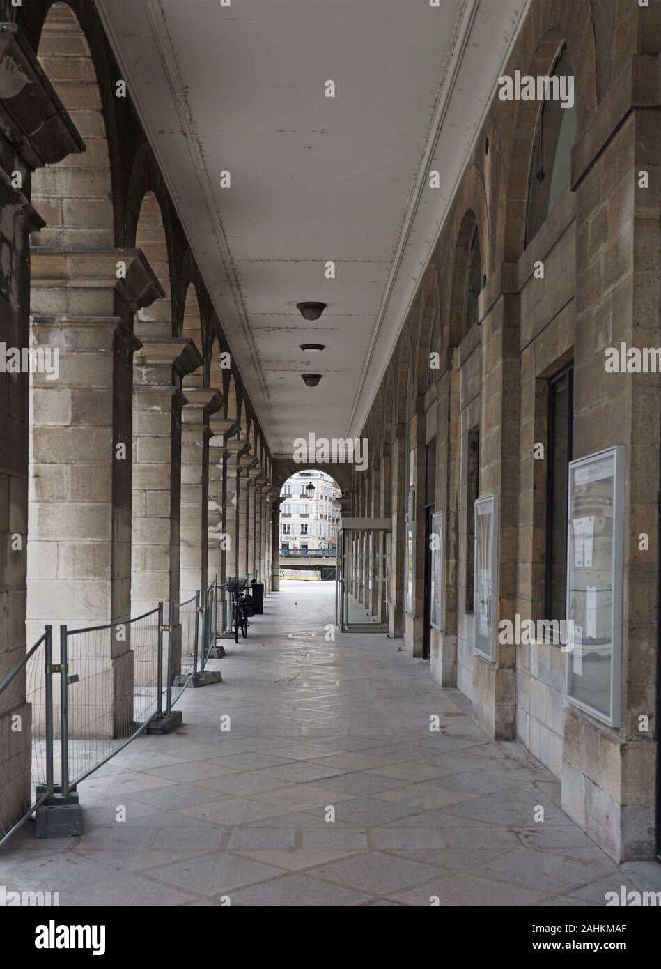 vertical image of receding covered stone arcade with paved footway ...