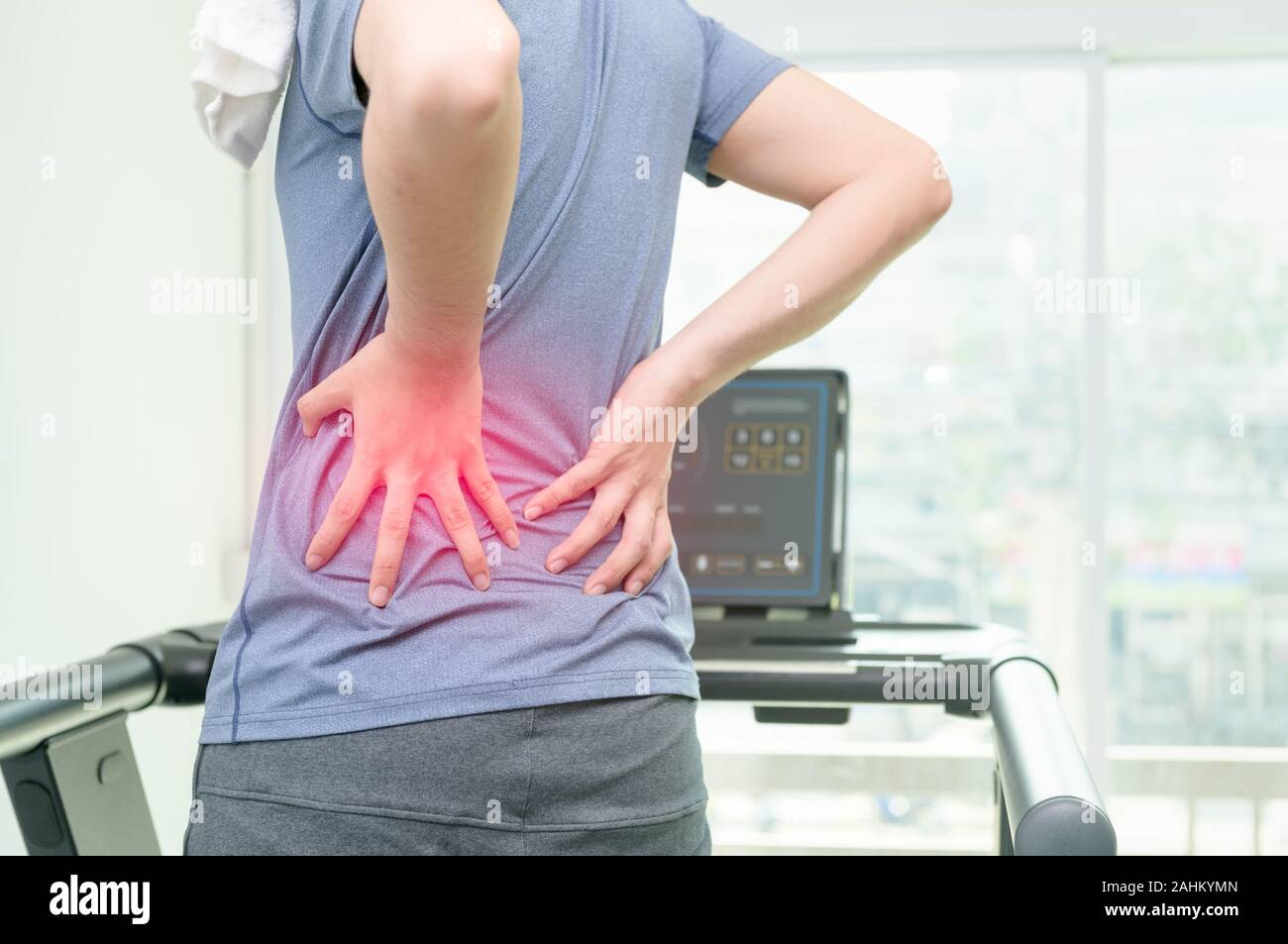 Back pain, close up young man has muscle injury during run on treadmill ...