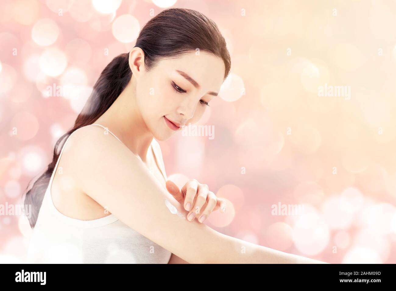 Beautiful young woman applying body lotion Stock Photo - Alamy
