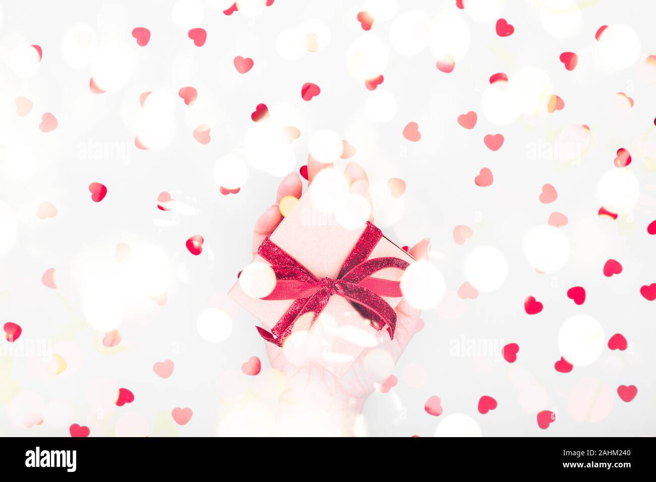 Craft box with red ribbon bow in female hand. Valentine day and eco ...