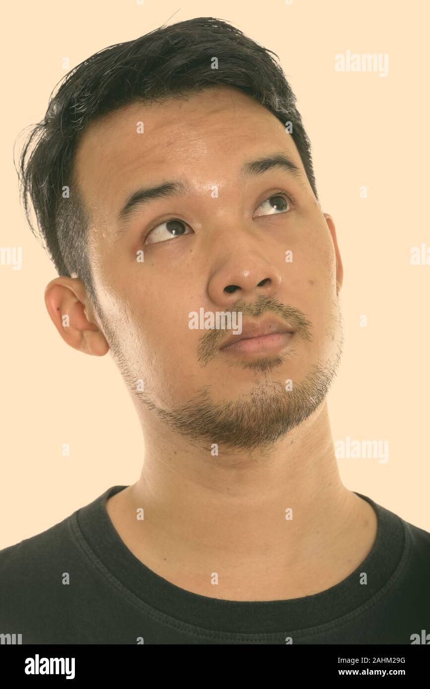 Face of young Asian man thinking while looking up Stock Photo - Alamy