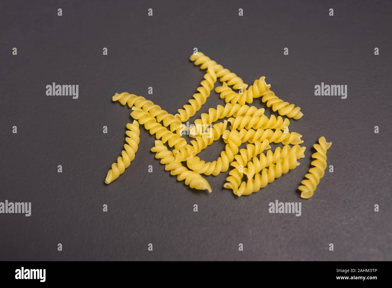 Raw pasta in the form of a spiral on dark grey background Stock Photo ...