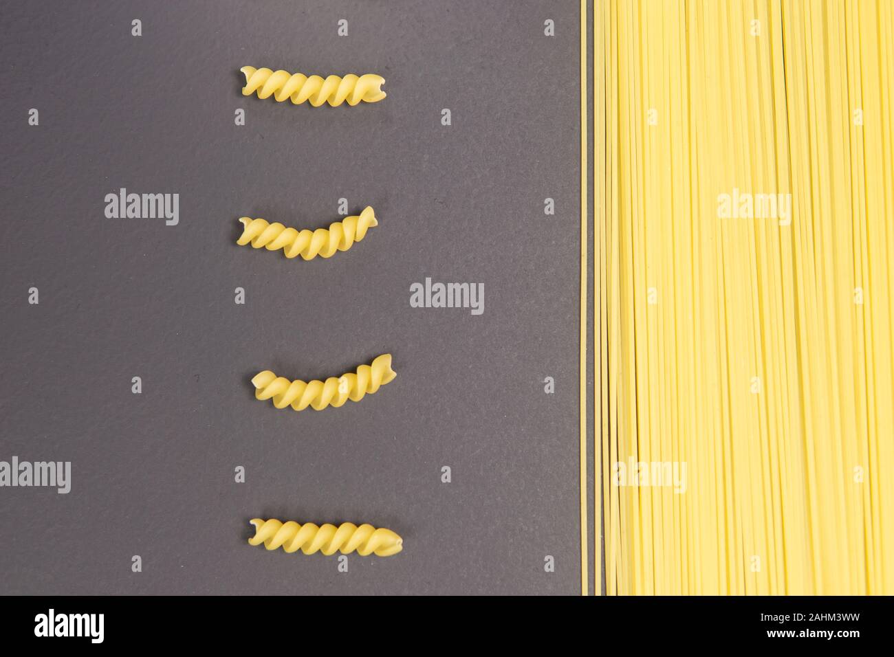 Raw Italian pasta in the form of a spiral and spaghetti on dark grey ...