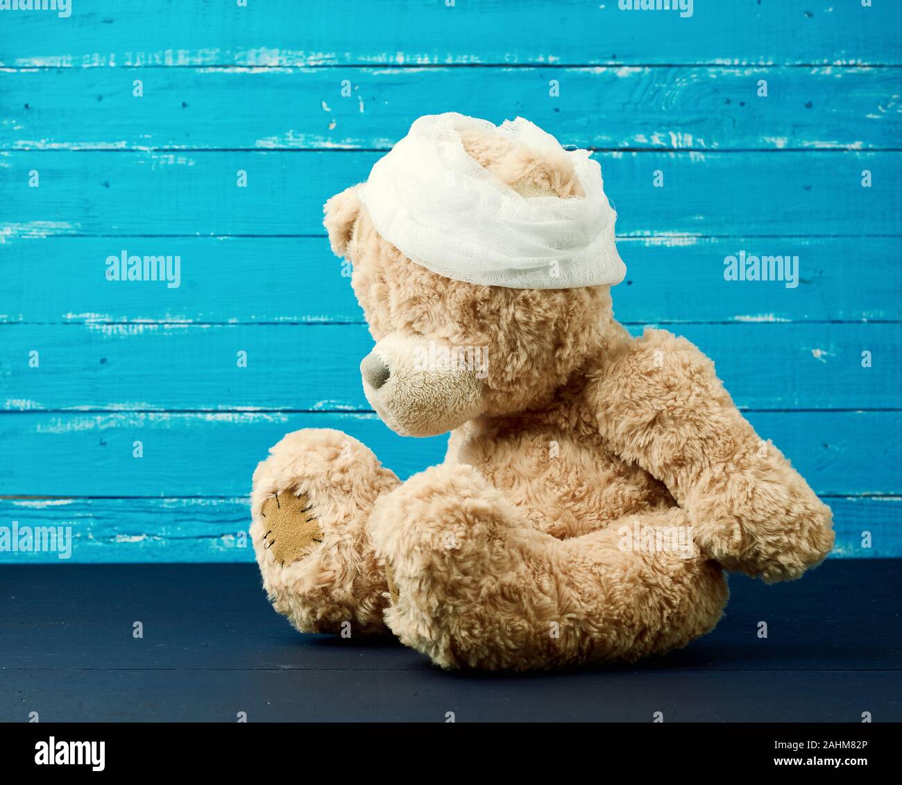 sad brown bear sits with bandaged white medical bandage head,injury and ...