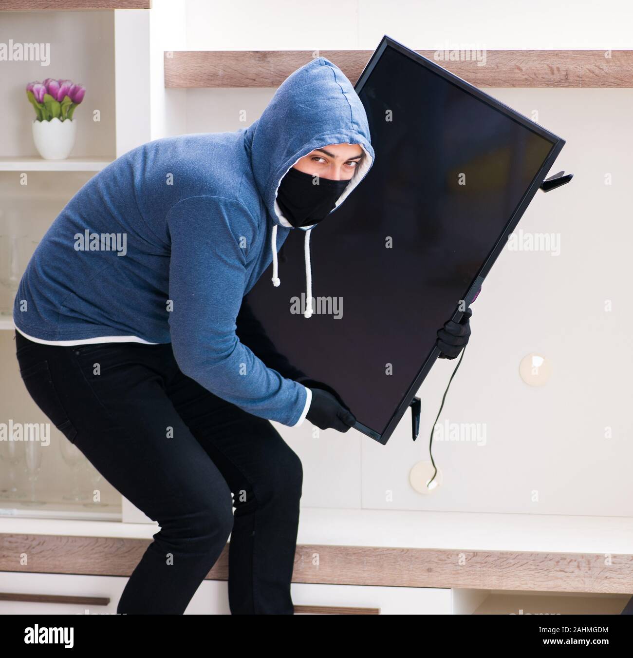 The man burglar stealing tv set from house Stock Photo - Alamy