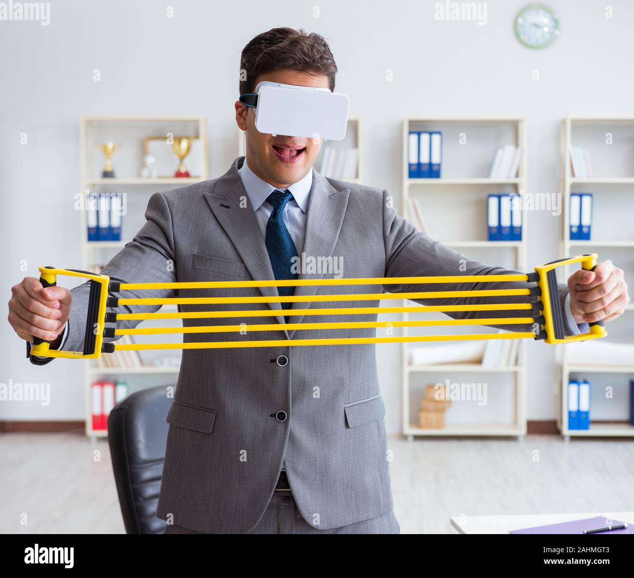 The businessman exercising with elastic expander wearing vr glasses ...