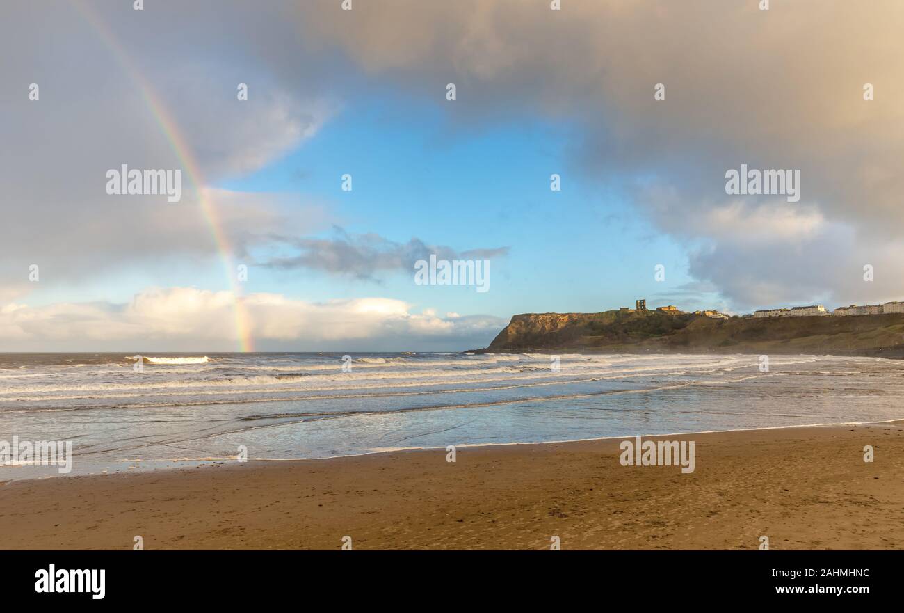 Waves roar towards a beach with a headland in the background and a ...