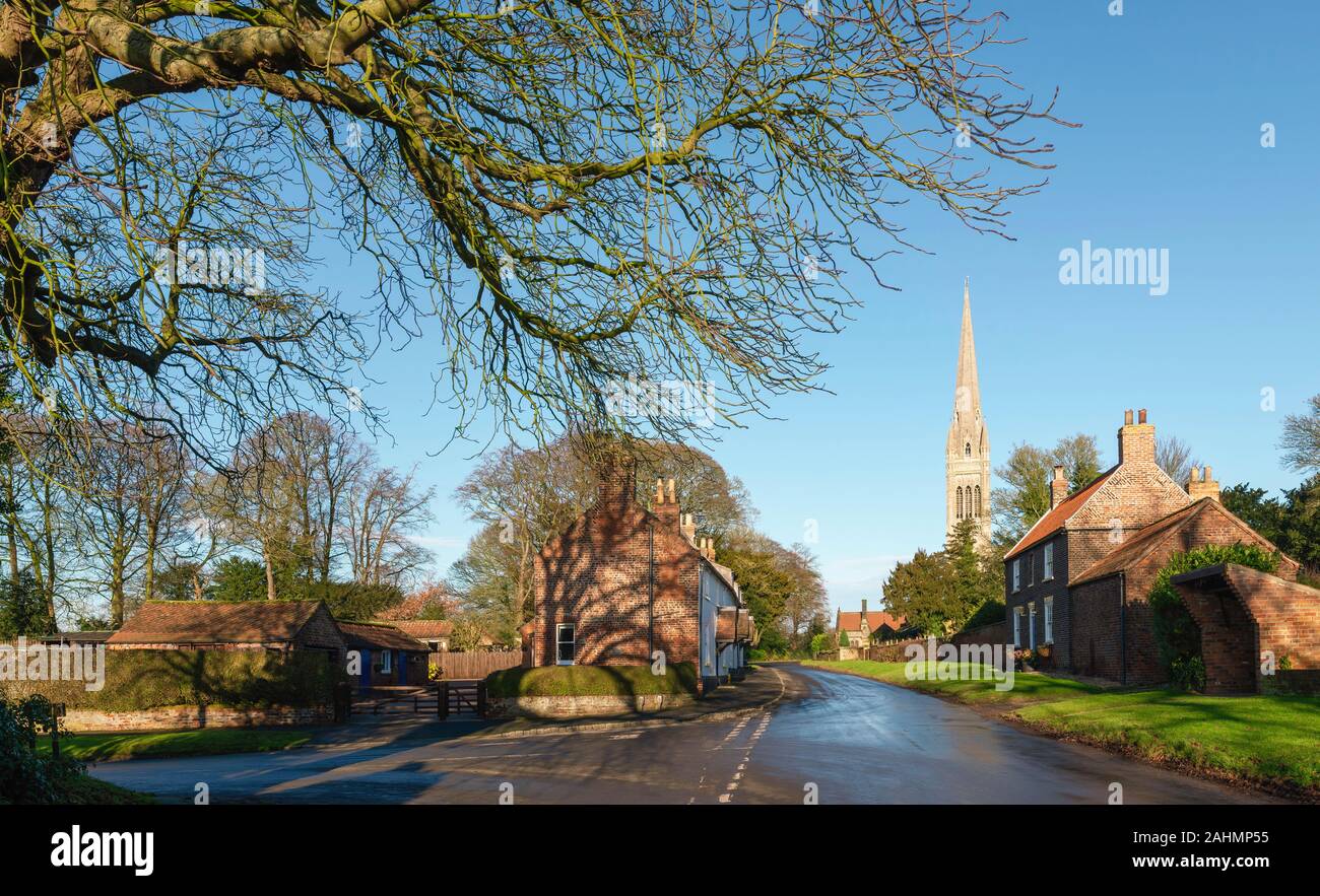 English village scene with ancient St Mary's Church flanked by houses ...