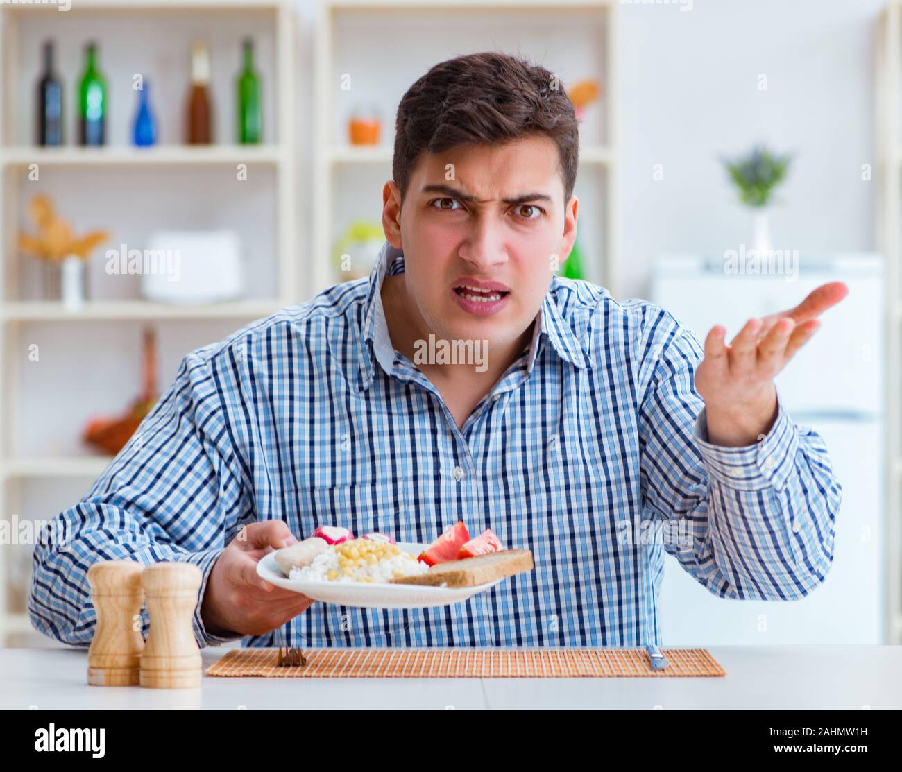 The young husband eating tasteless food at home for lunch Stock Photo ...