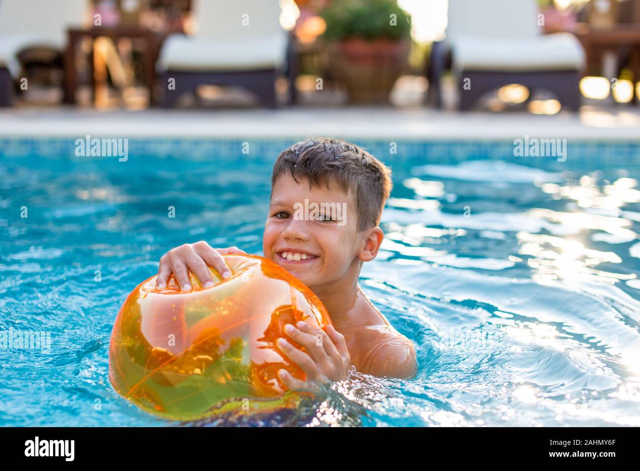 Happy little Caucasian boy holding inflatable ball in swimming pool ...