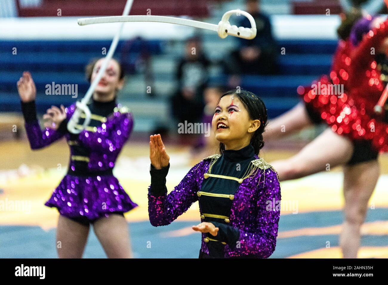 A young Asian-American woman prepares to catch a sword while performing ...
