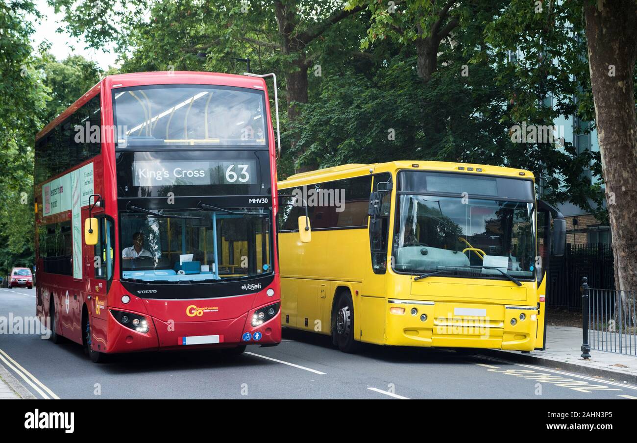 A red London bus alongside a bright yellow coach waiting to collect ...