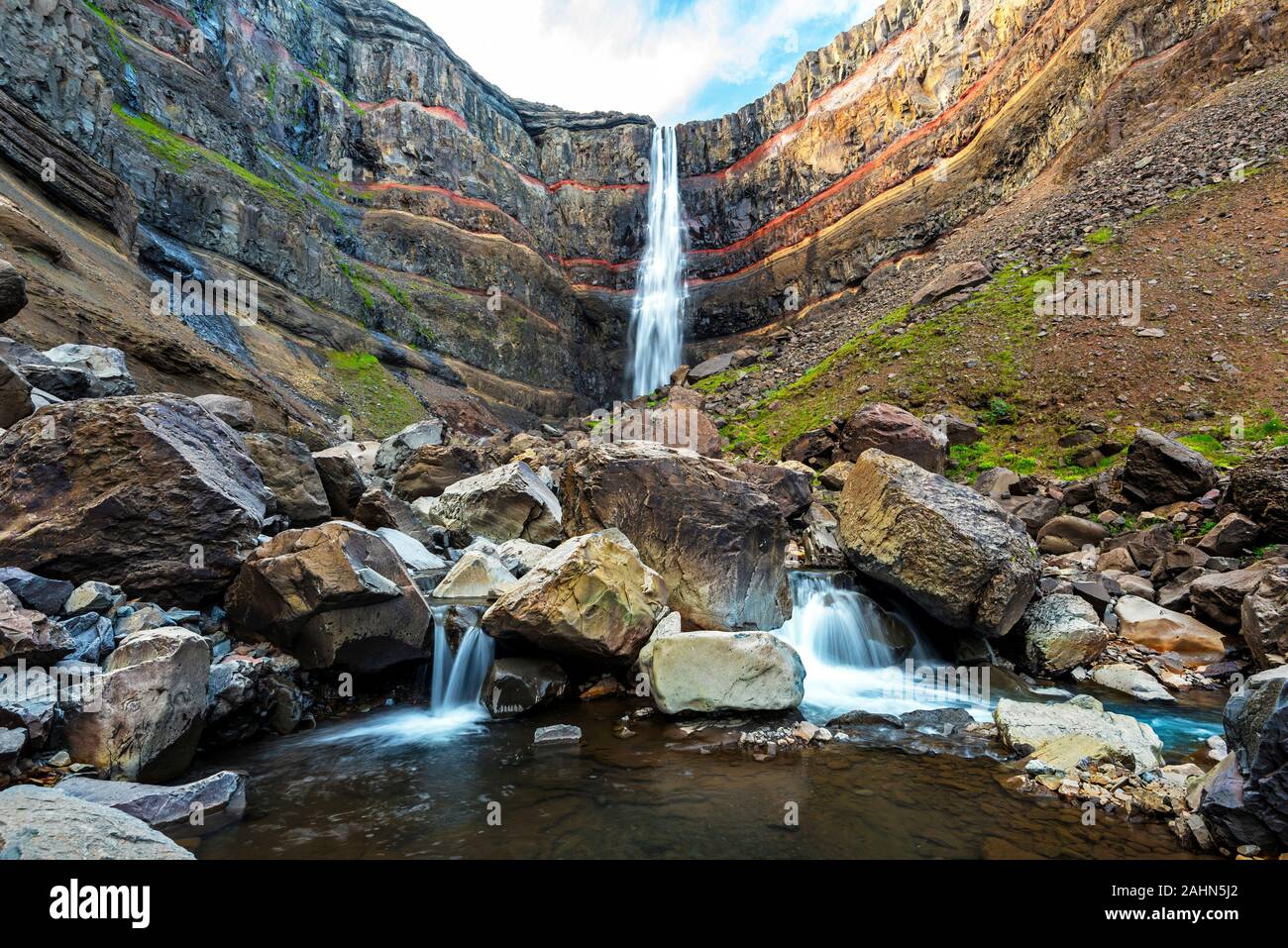 Hengifoss waterfall and the wall of basaltic strata with thin, red and ...