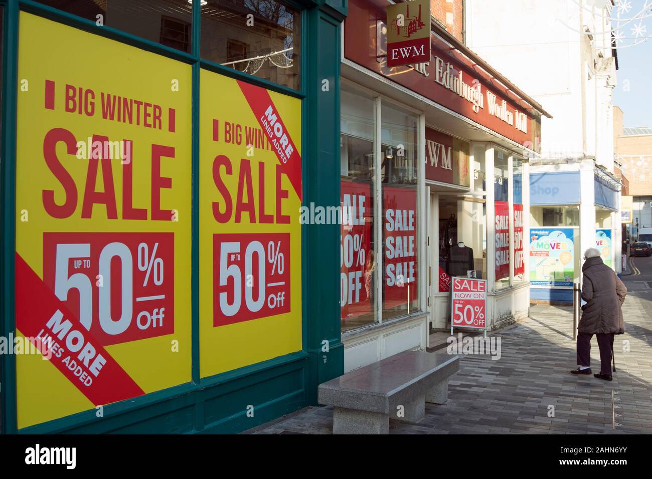 an elderly person passing shop sale signs offering 50% off, in kingston ...