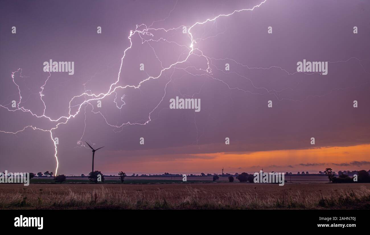 Severe lightning at sunrise pictured around a wind turbine Stock Photo ...