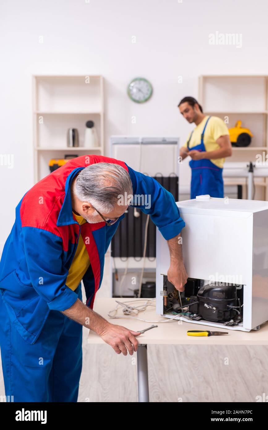 The two contractors repairing fridge at workshop Stock Photo - Alamy