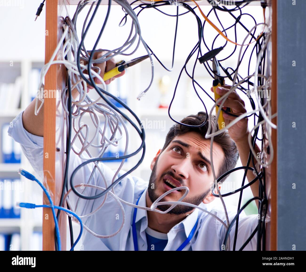The electrician trying to untangle wires in repair concept Stock Photo ...