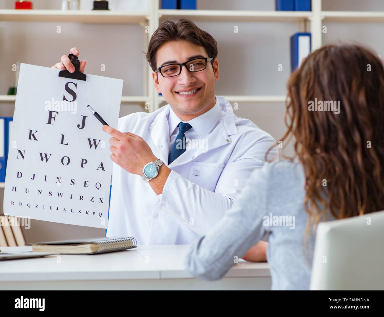 The doctor optician with letter chart conducting an eye test check ...