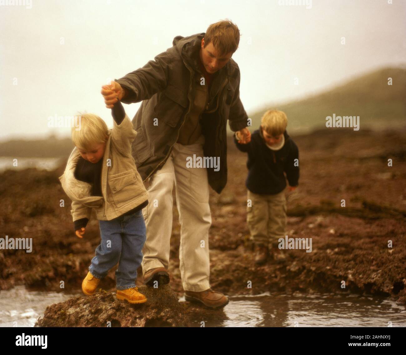 Father and two sons exploring rock pools Stock Photo - Alamy