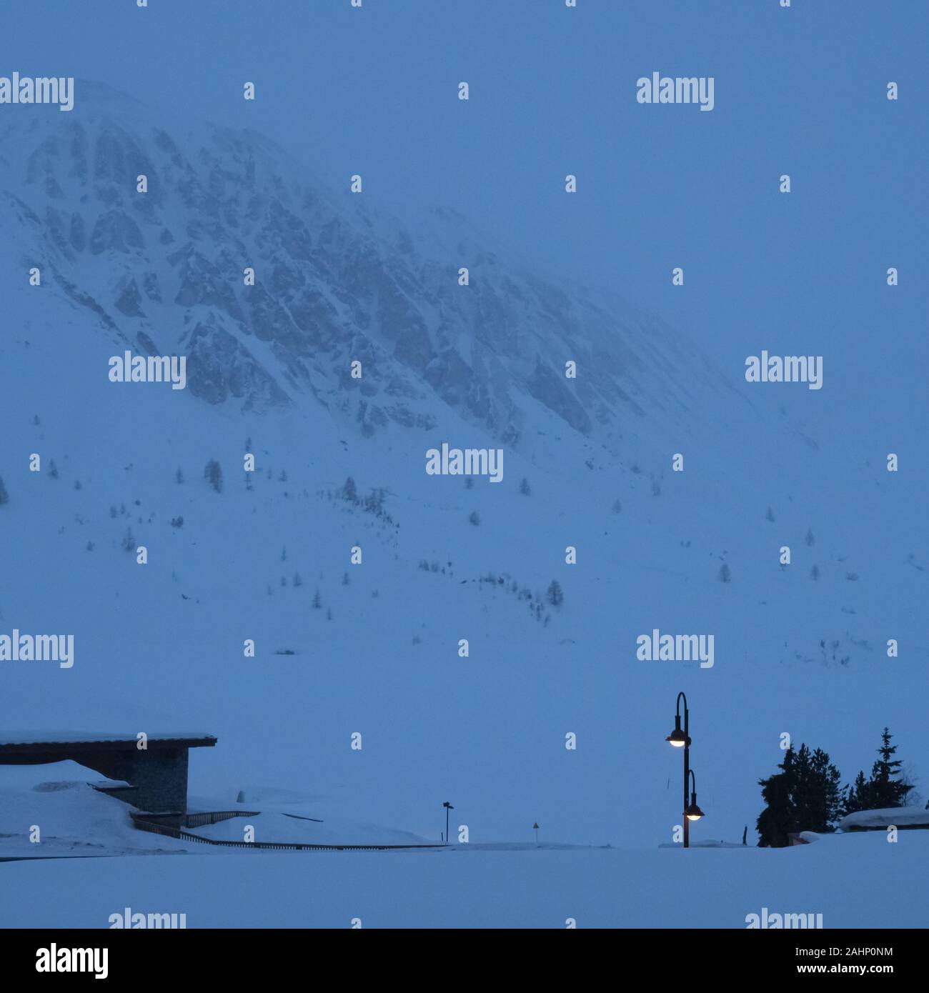 A lit street lamp lights at dawn with snowy snow mountain background ...