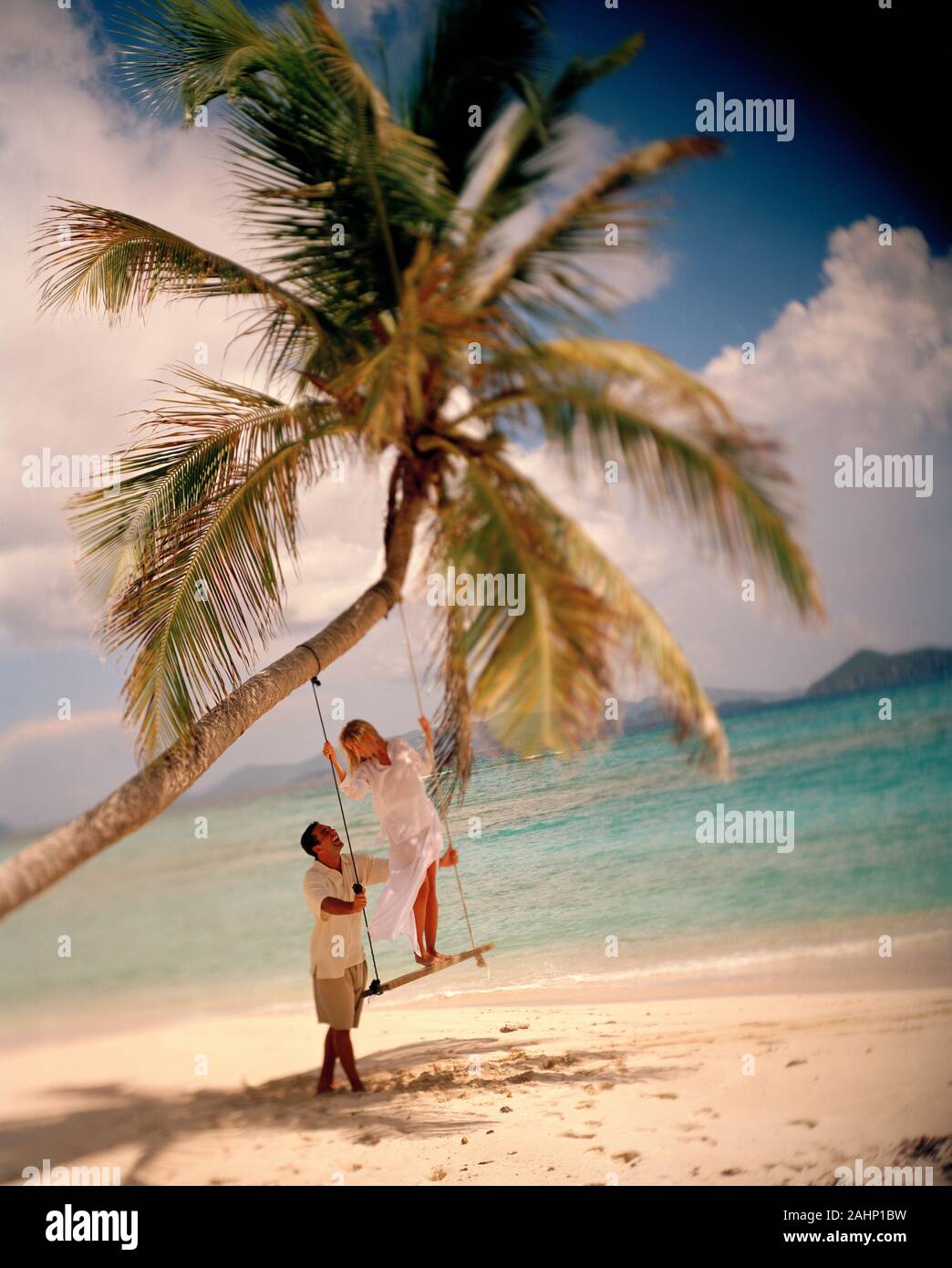 Man pushing a woman on a swing Stock Photo - Alamy