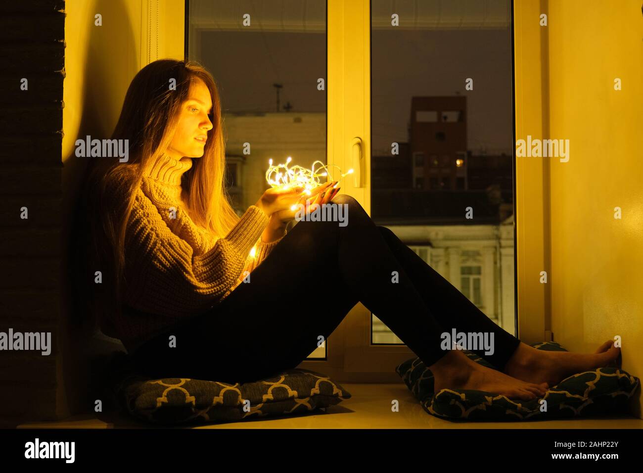 Winter portrait of young beautiful woman sitting near window on ...