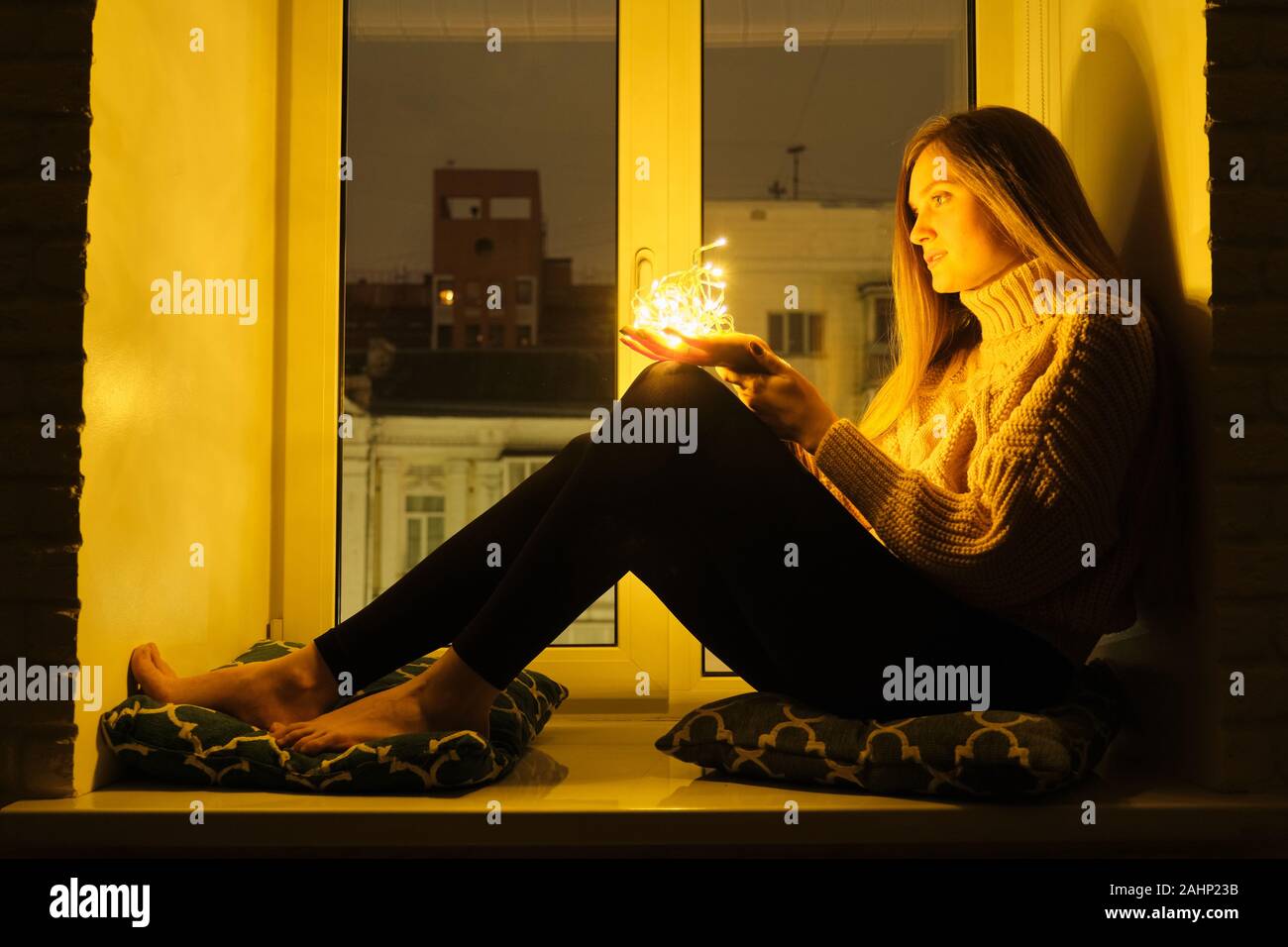 Winter portrait of young beautiful woman sitting near window on ...