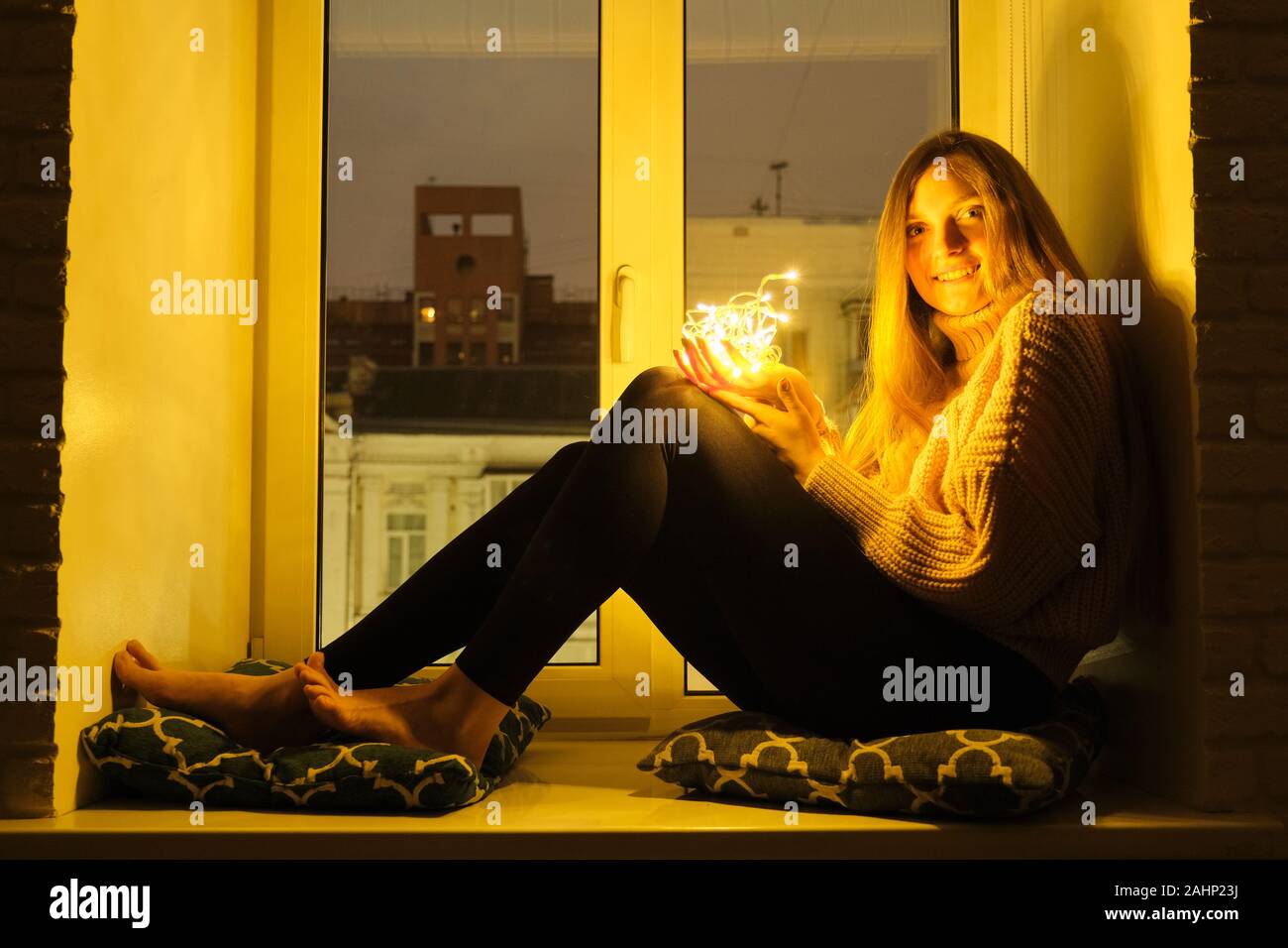 Winter portrait of young beautiful woman sitting near window on ...