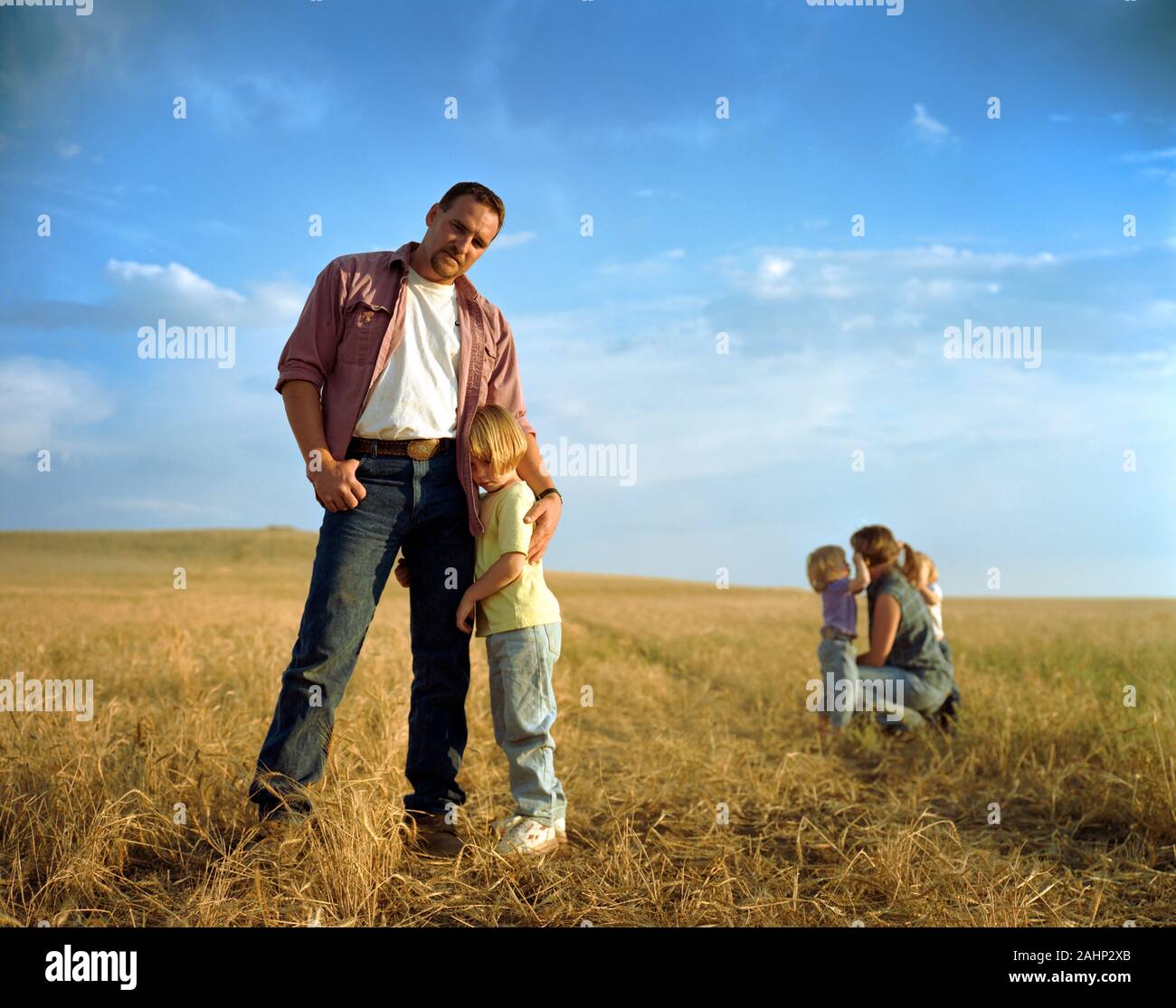 Man standing in a field with his family looking concerned Stock Photo ...