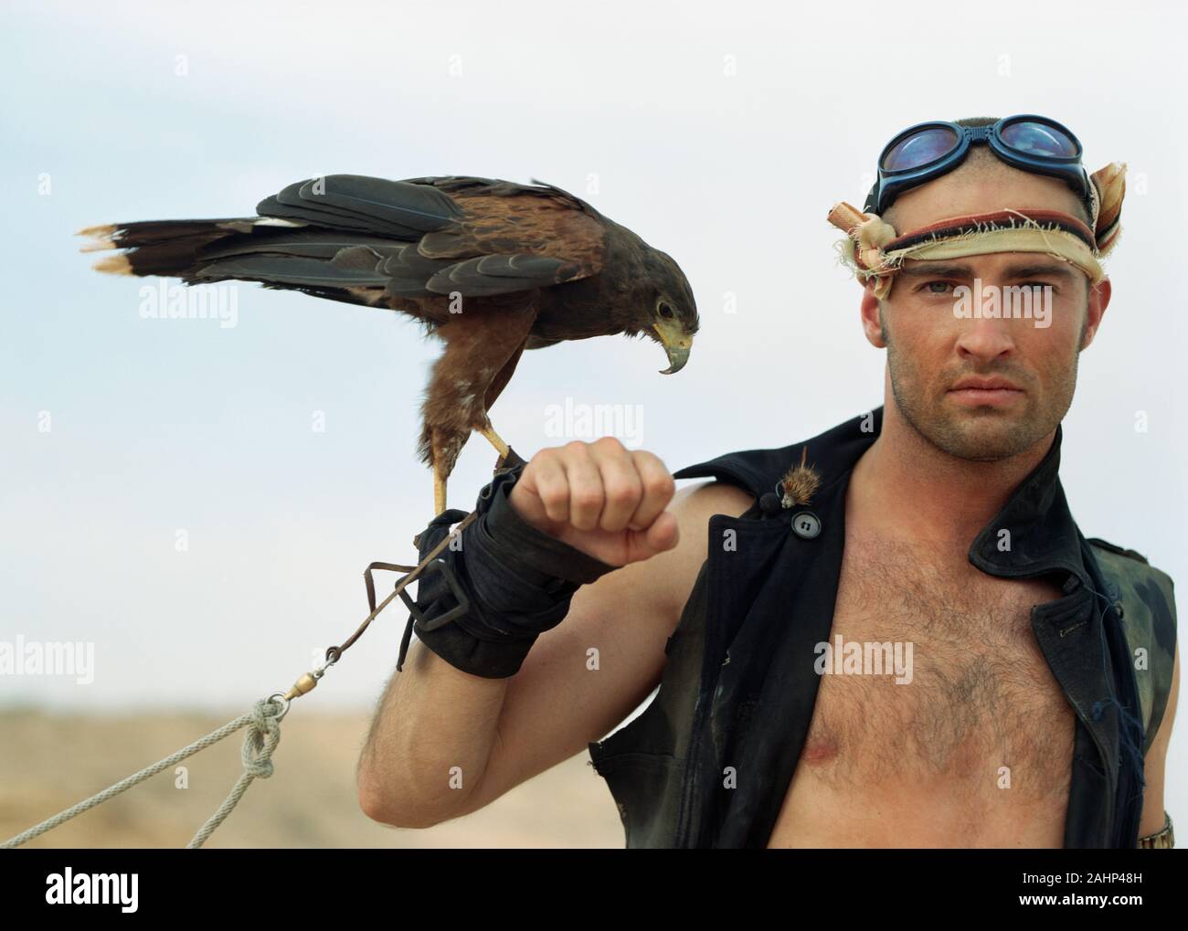 Portrait of a young man standing with a bird of prey perched on his ...