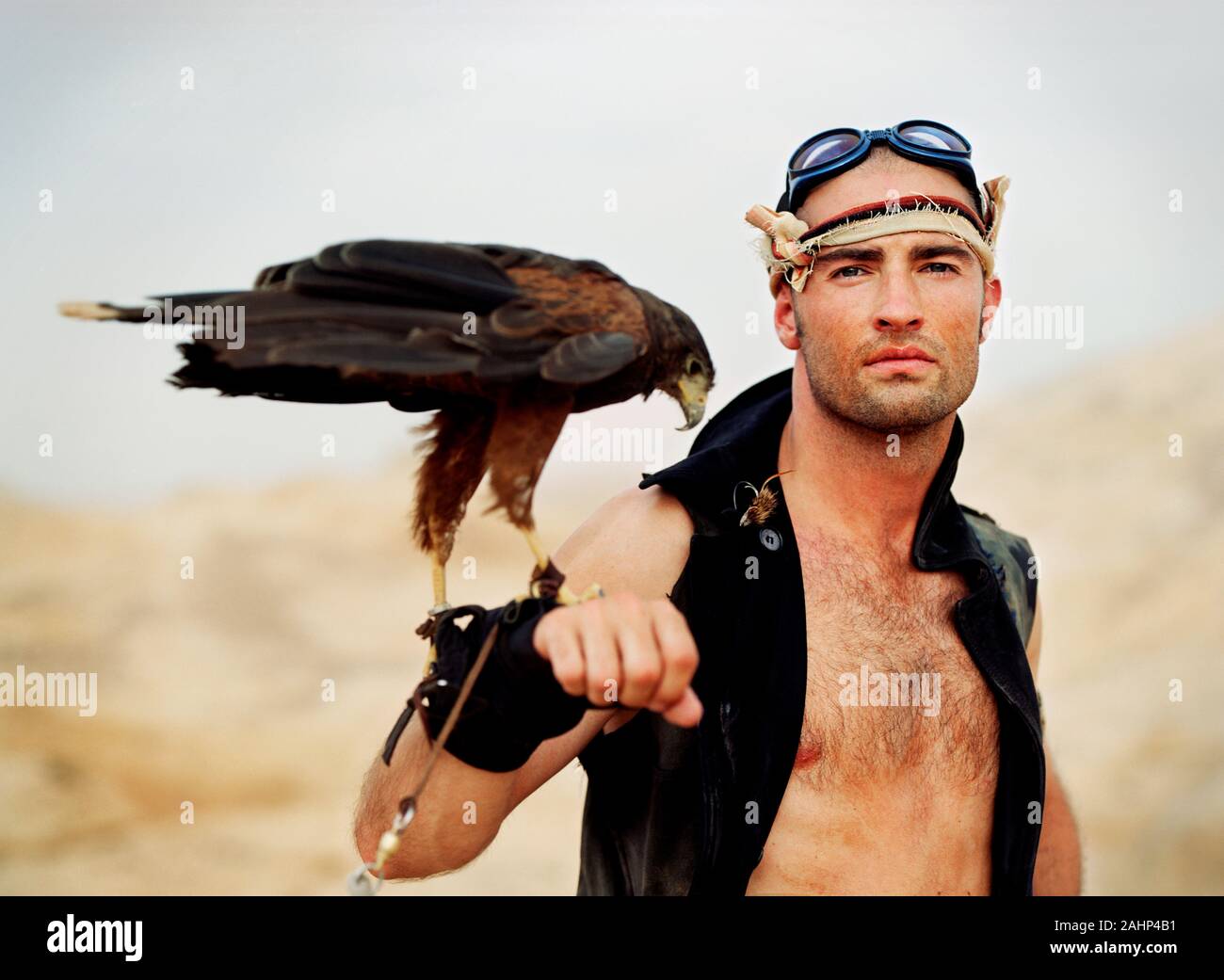 Portrait of an adventurous young man holding a bird of prey on his ...