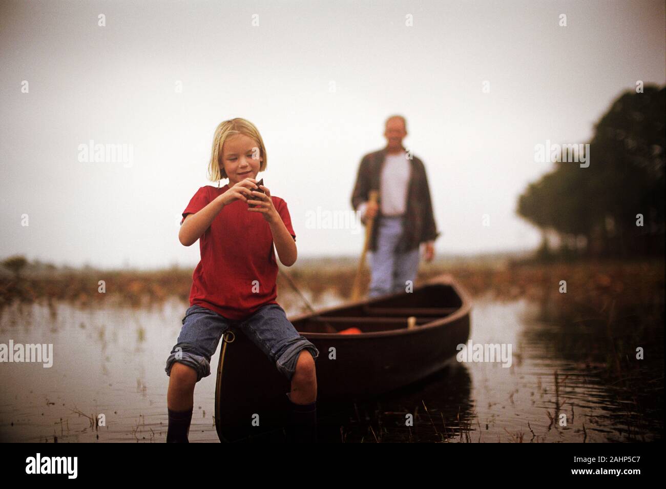 Front view of an engrossed kid seated on a boat Stock Photo - Alamy