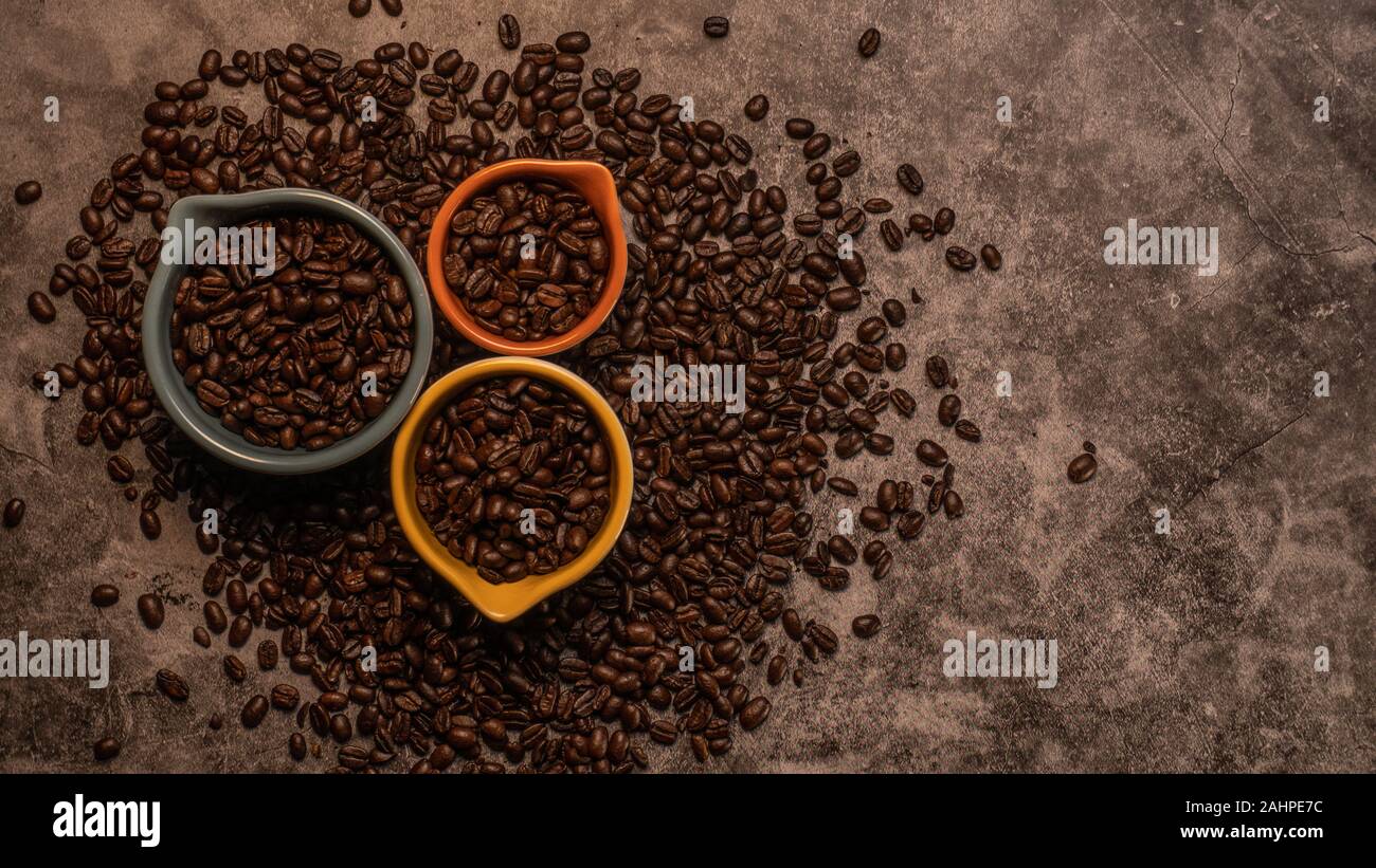 Fresh raw organic coffee beans in many colorful cups with varied sizes ...