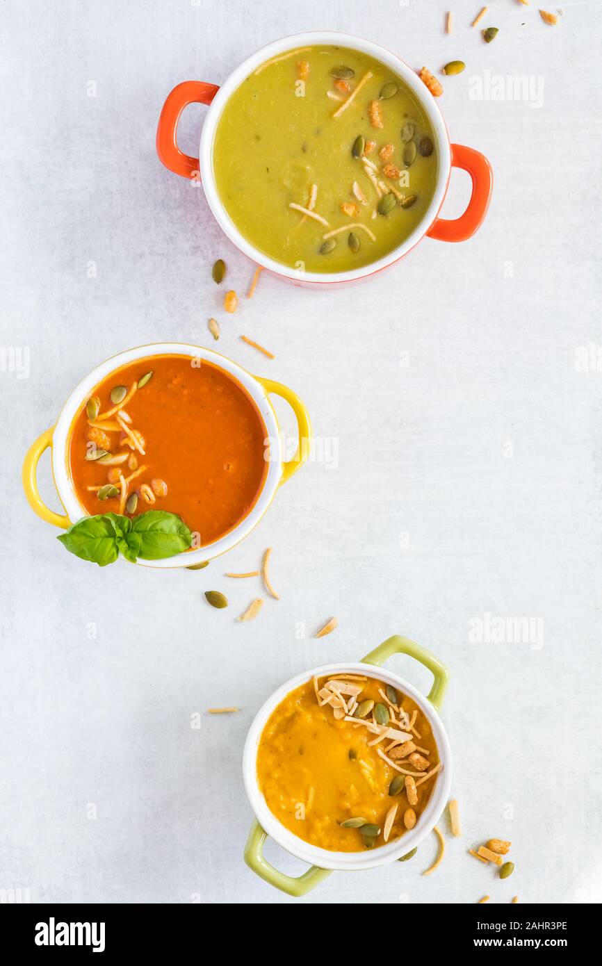 Top down view of three bowls of different kinds of hot soup ready for ...